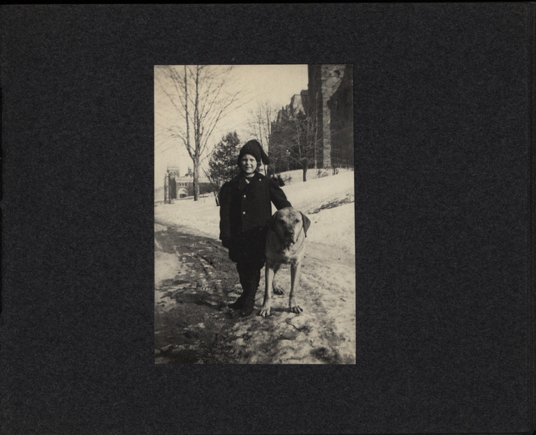 Girl in coat standing with dog, Linderman library in the background ...