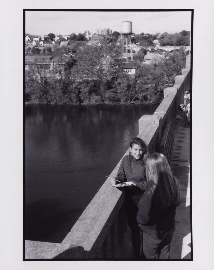 Lora Booker, psychology major, standing on bridge speaking to girl ...